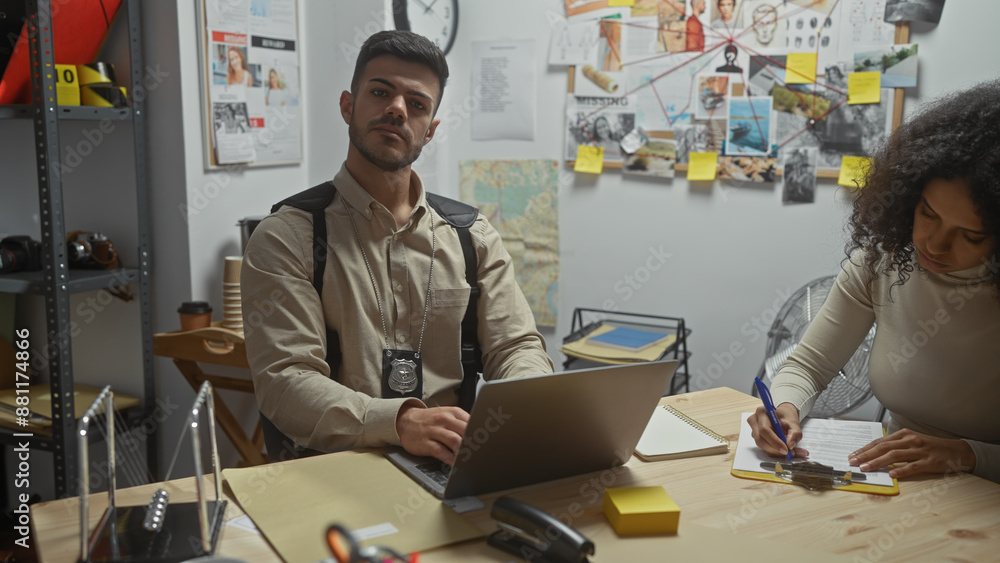 Man and woman detectives working in a cluttered police station office ...