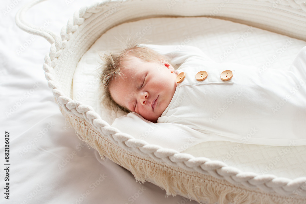 Cute Caucasian newborn baby girl sleeping in a white outfit in a Moses ...