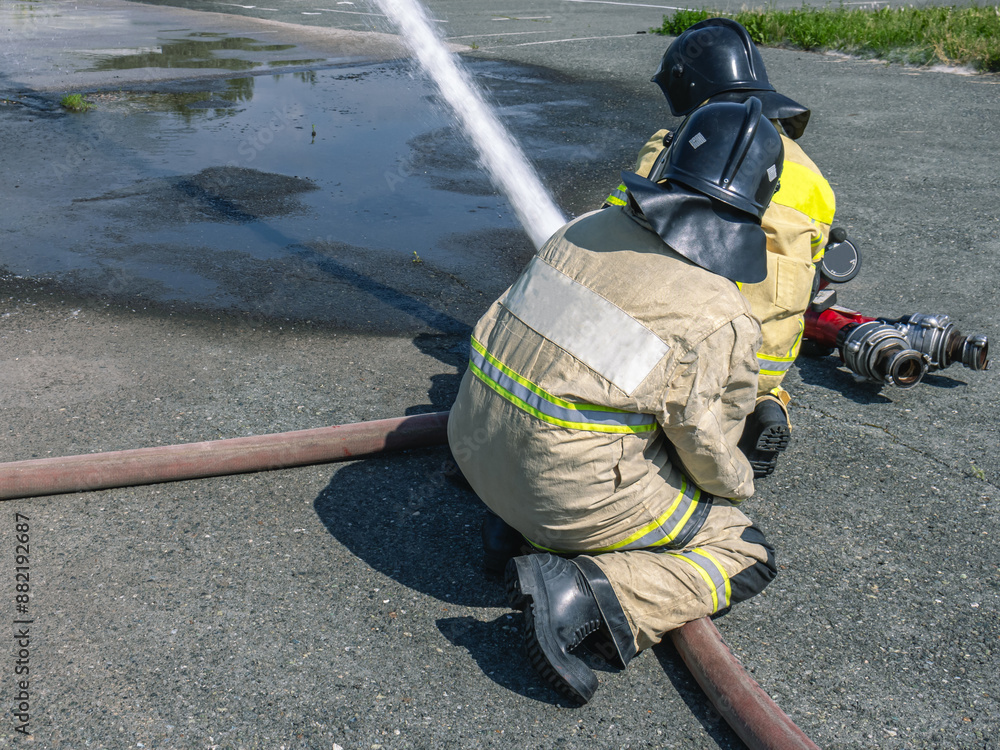 Firefighters in protective clothing hold the carriage fire barrel when ...
