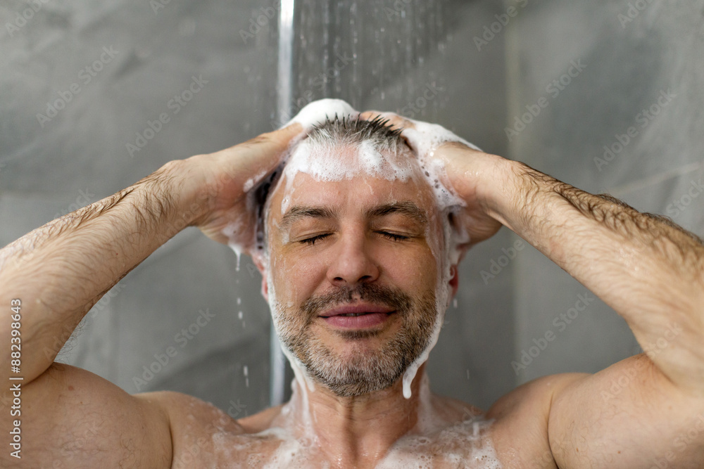 Man washing head with shampoo while taking shower standing with eyes ...
