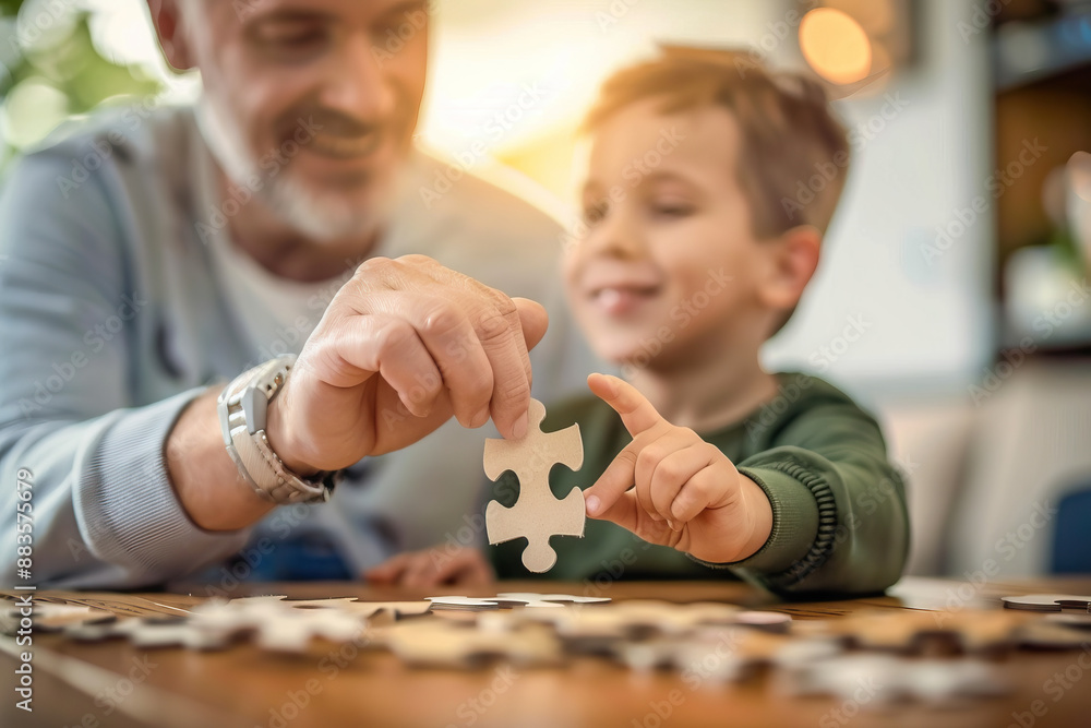 Grandfather and grandson with light skin working on a puzzle together ...