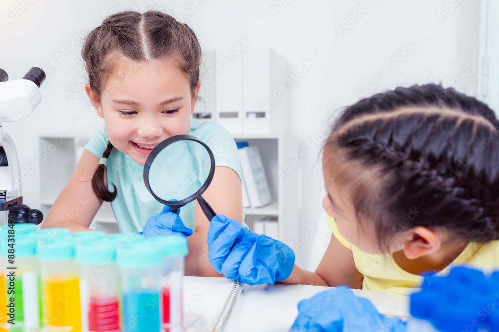 Two young girls enthusiastically engage in science activity, using ...