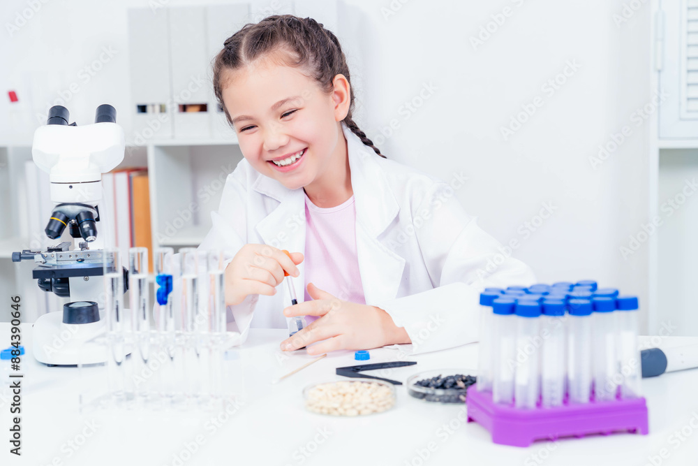 Young girl in white lab coat smile as she conducts a science experiment ...