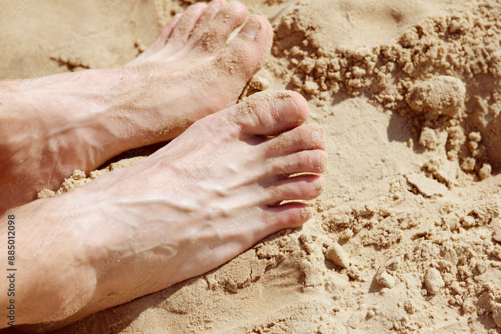 Close-up of feet buried in sand at the beach, highlighting toes with a ...