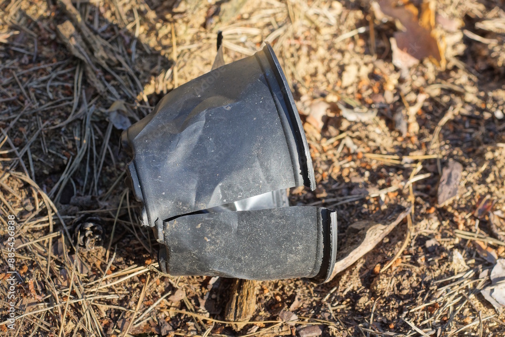 garbage from one black broken plastic flowerpot with a crack lies on ...