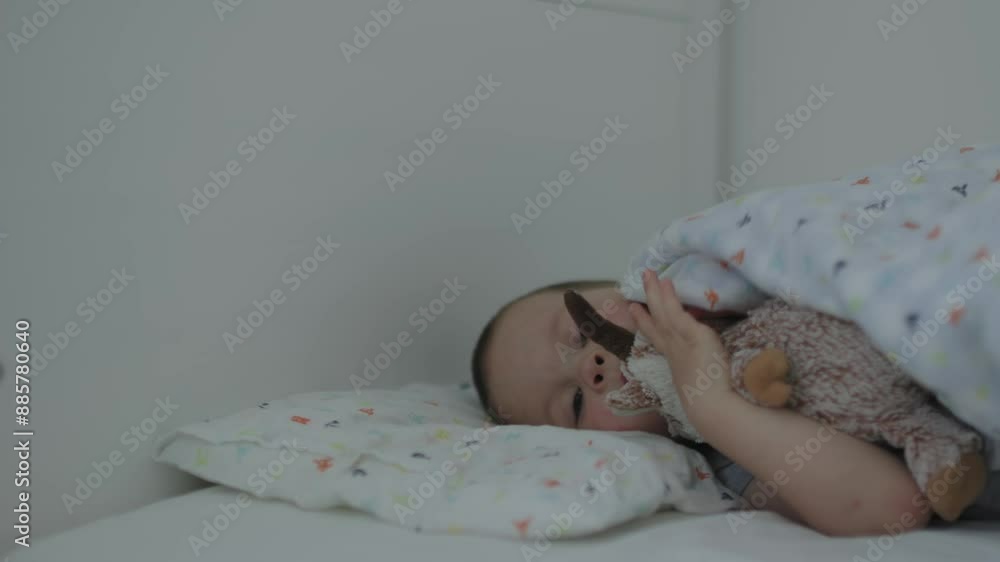 Bedtime child lies under covers hugs favorite fluffy toy. Hugs with ...