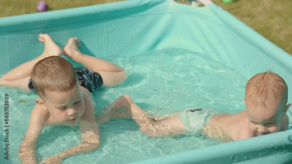 Laughing gleefully two boys children splash play in inflatable pool ...