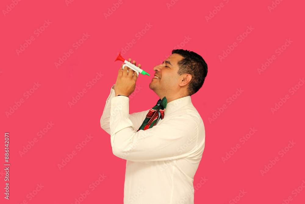 Dark-skinned Latino adult man plays a toy tricolor trumpet with a bow ...
