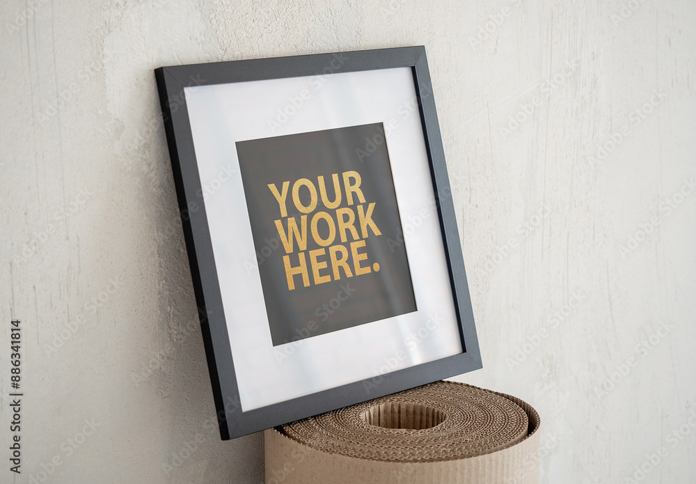 Square poster with black frame mockup standing on a roll of cardboard ...