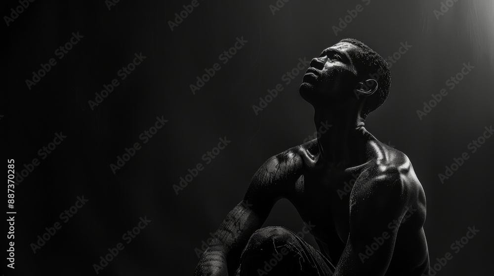 Artistic photography featuring a black man sitting in a half body pose ...