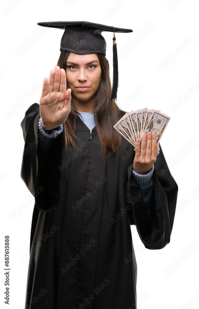 Young hispanic woman wearing graduated uniform holding dollars with ...