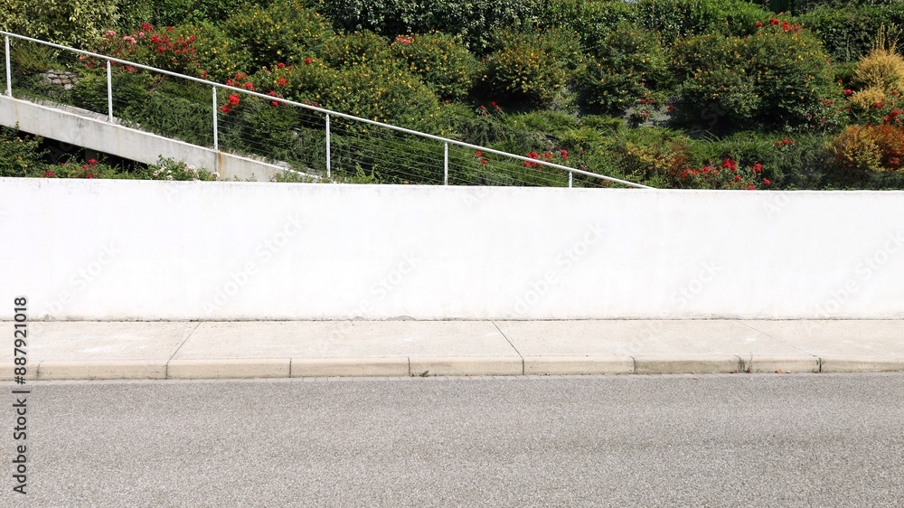 White plaster fence with flowering garden and a staircase on behind ...