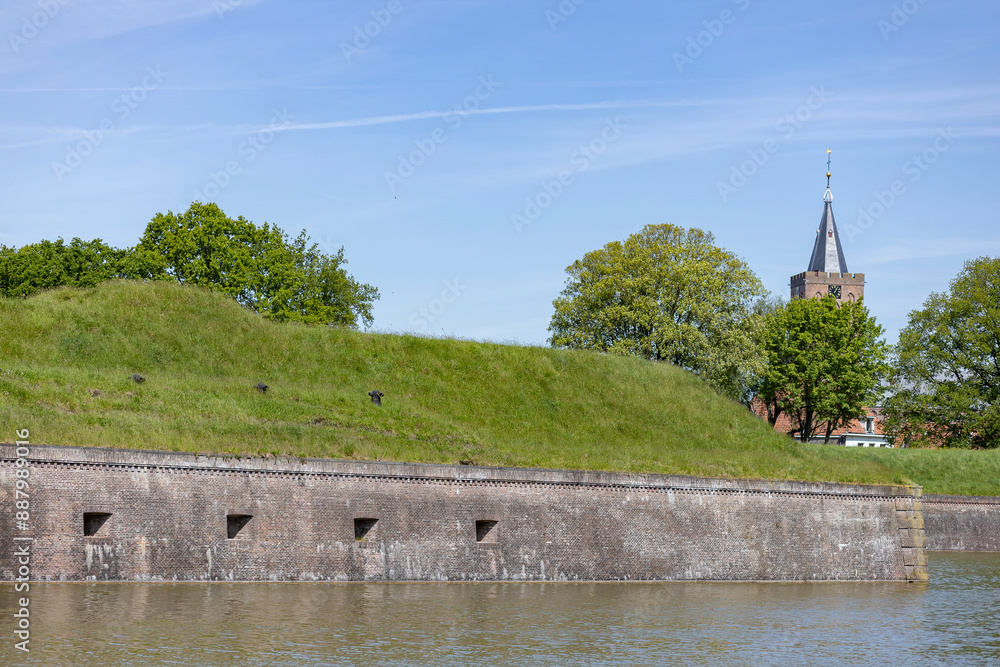 Greenery with church tower on top and behind Naarden Vesting moated ...