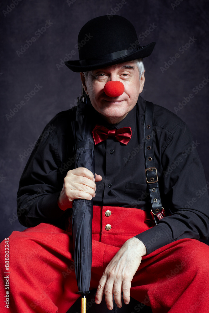 Clown with umbrella on dark background. Dressed in red pants and a ...