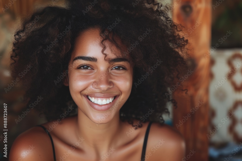 Happy dark skinned woman with shaggy hair smiles indoors on her first ...