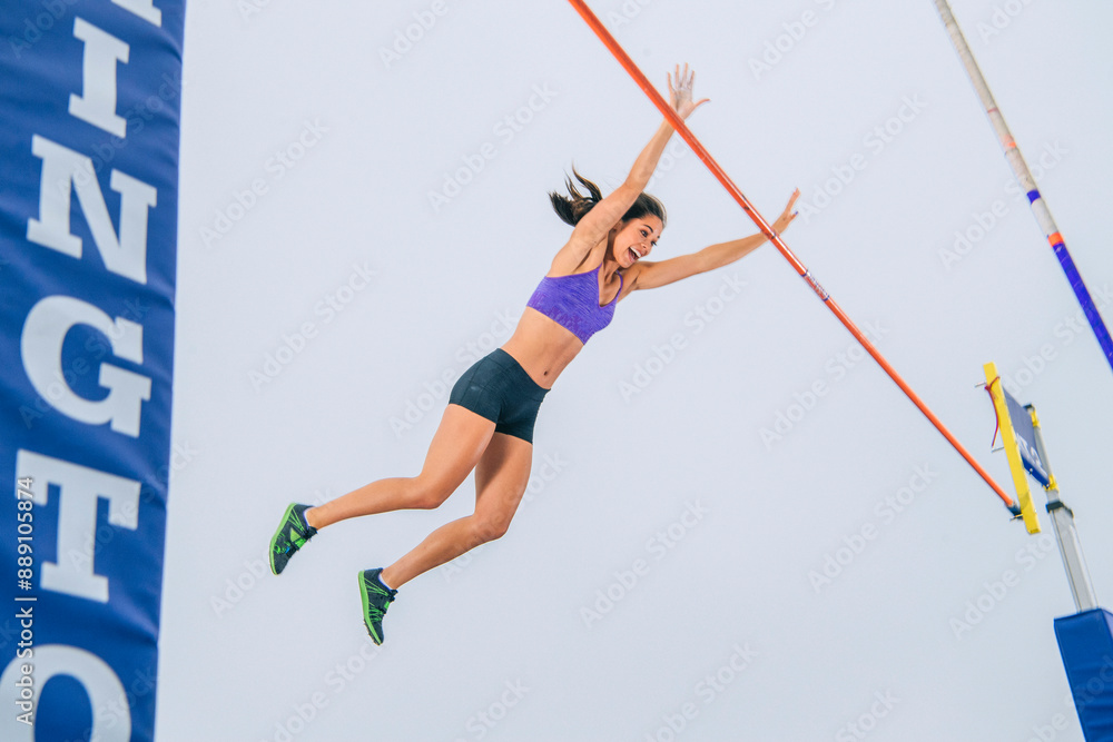 Female athlete jumping over a high bar in a pole vaulting competition ...
