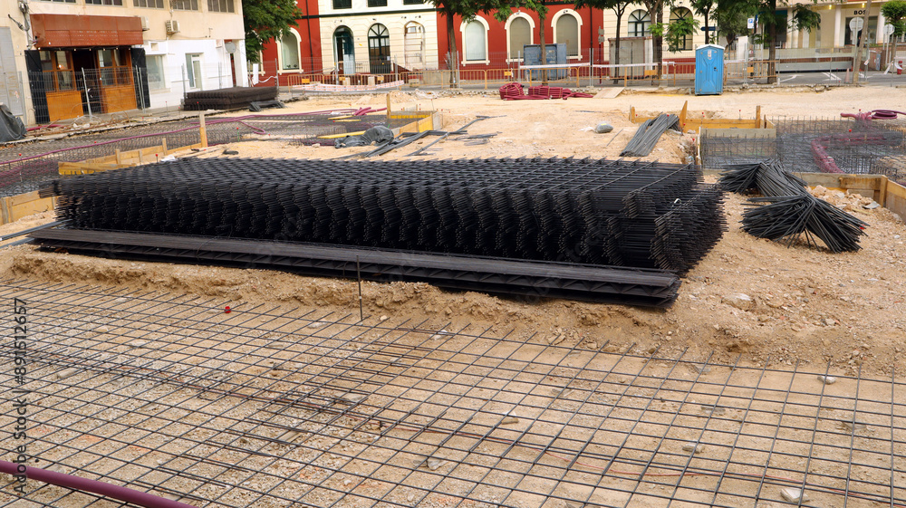 Pile of rebar mesh is stacked on ground at construction site. Mesh is ...