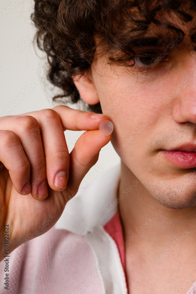 Man is applying acne pimple patch on his face to heal from zits ...