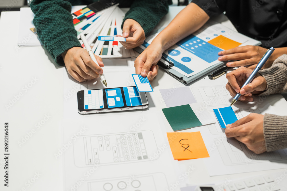 A group of people collaborates around a desk, discussing and reviewing ...
