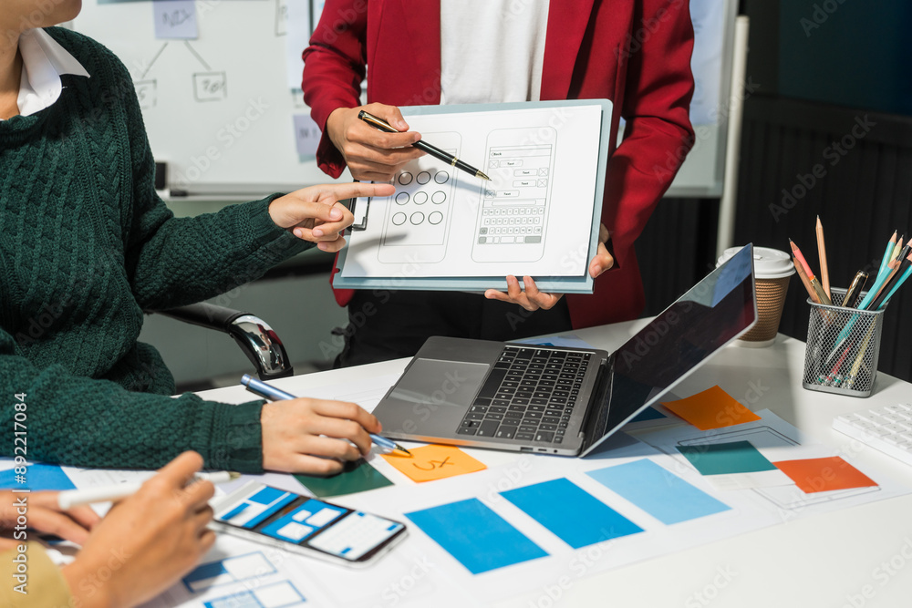 A group of people collaborates around a desk, discussing and reviewing ...