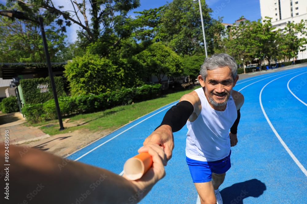 Senior Asian athlete is practicing running with relay baton in the ...