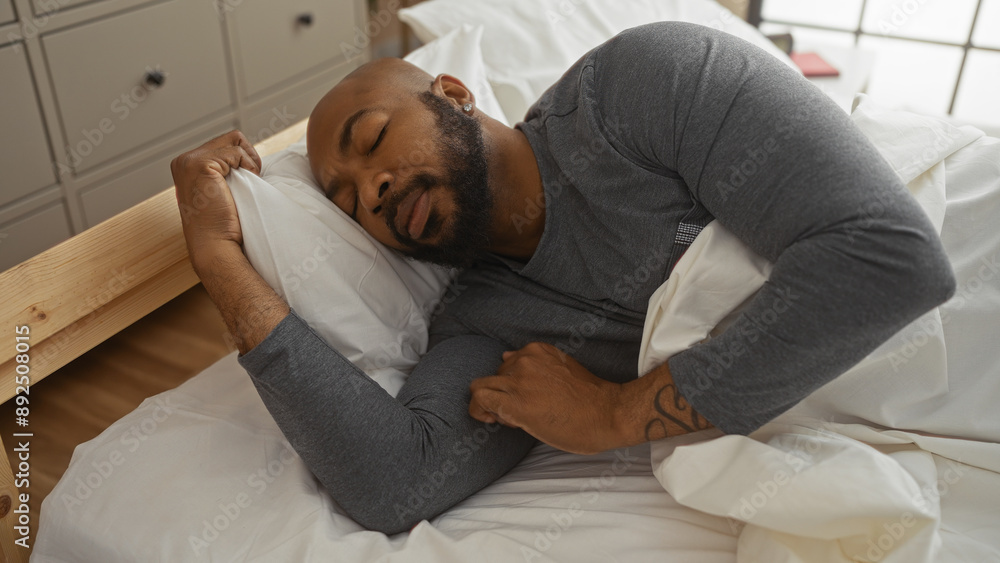 Handsome young african man sleeping in bed located in a cozy bedroom ...