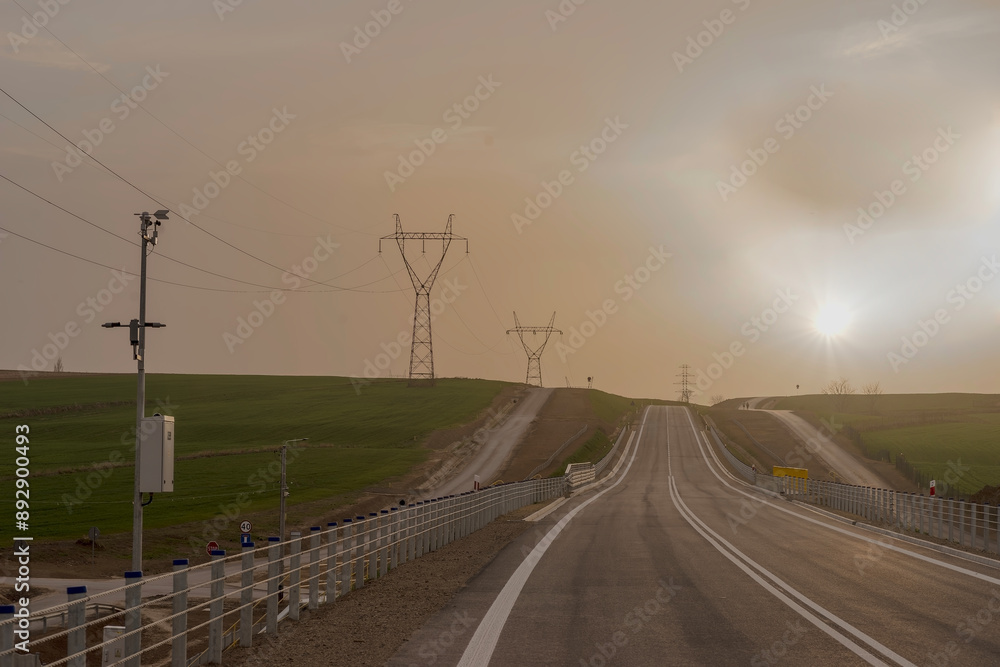 Pusta droga o zachodzie słońca wczesną wiosną. Na skraju drogi mała ...