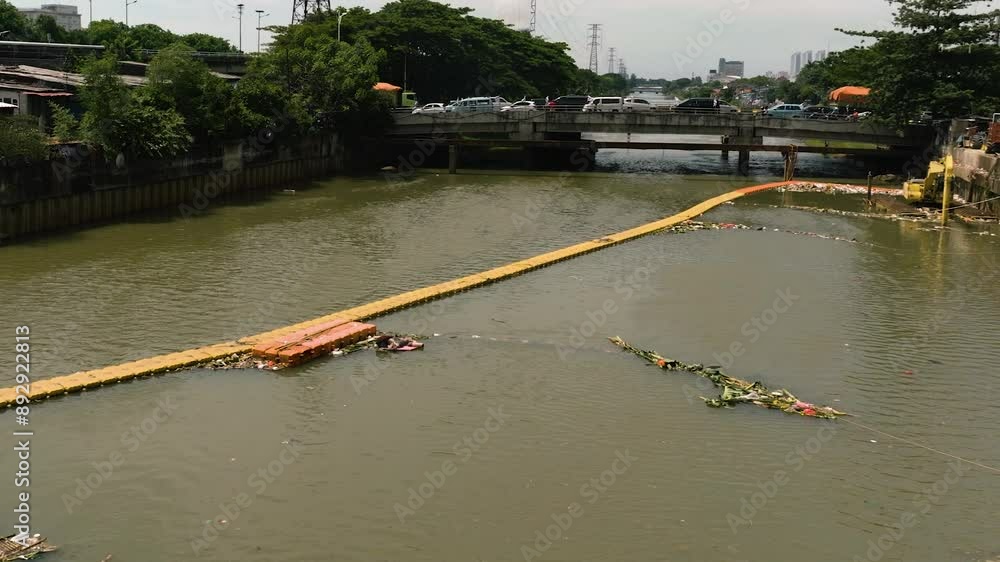 Floating trash catcher on the polluted river Ciliwung among the slums ...