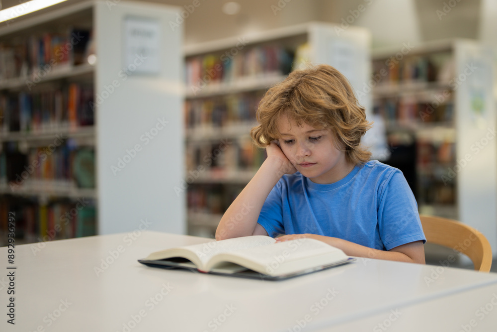 Foto de School boy read book in school library. Smart kids reading ...