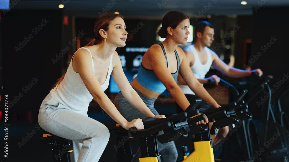 Sportive young woman doing spin bike exercises in well-equipped gym ...