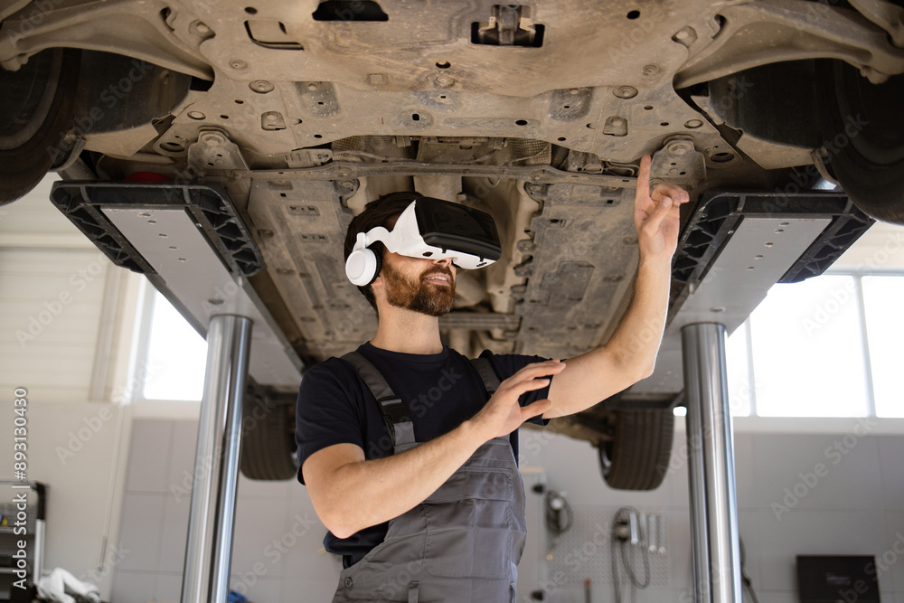 Mechanic examining technical condition of car on lift with using ...