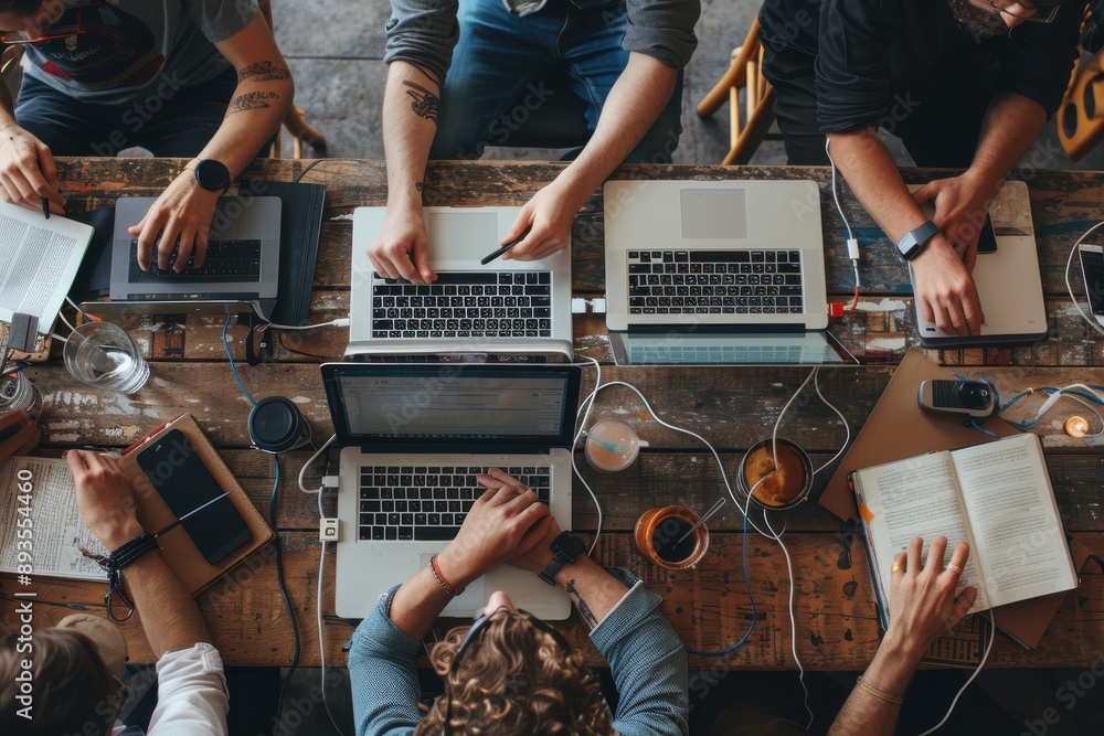 An overhead shot of people working on laptops in a collaborative ...