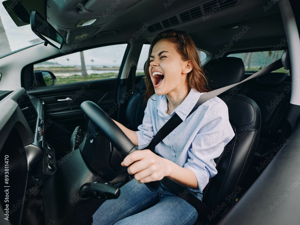 Woman laughing, driving car with hands on steering wheel and mouth wide ...
