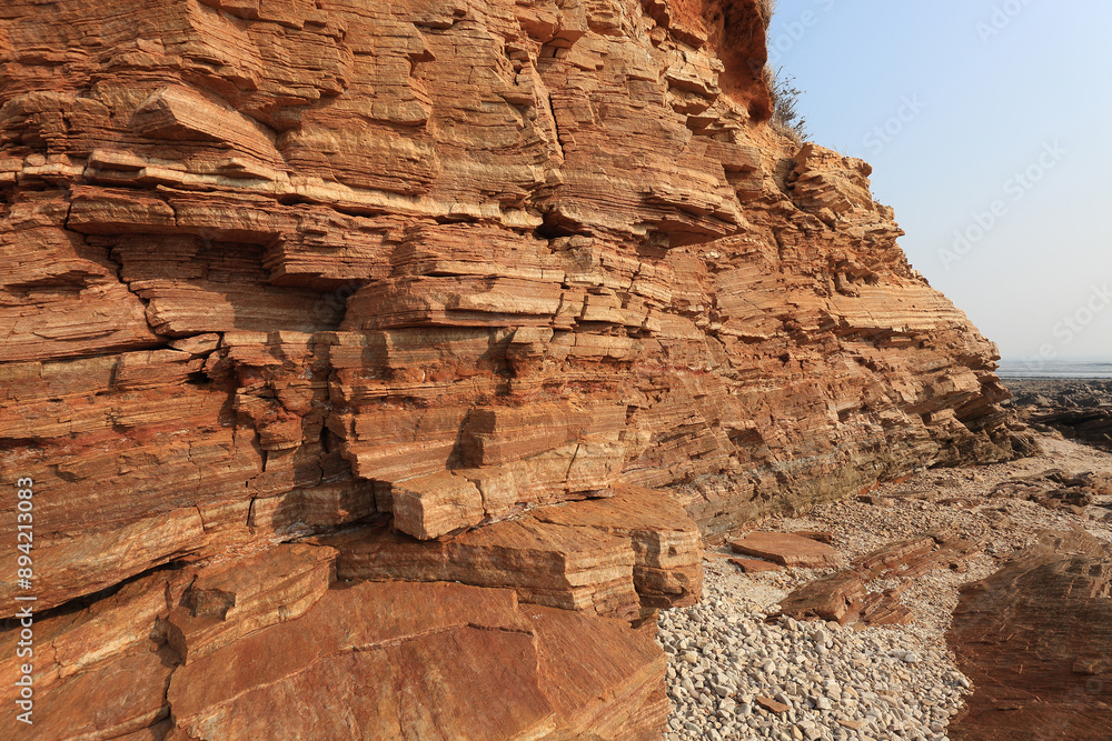 Morning view of red sedimentary rock sea rock and cliff at low tide on ...