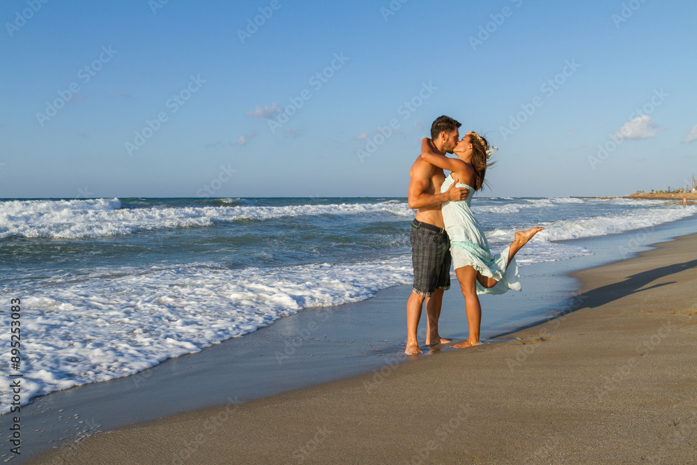 Young couple kissing at the beach in a late summer hazy day at dusk ...