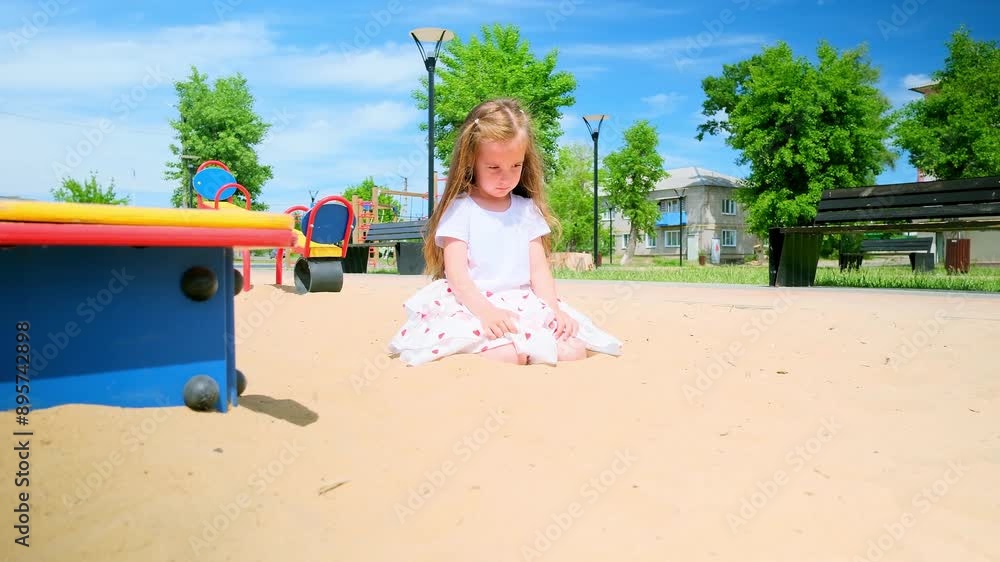 Upset crying baby girl on the playground at sand. Children playing ...