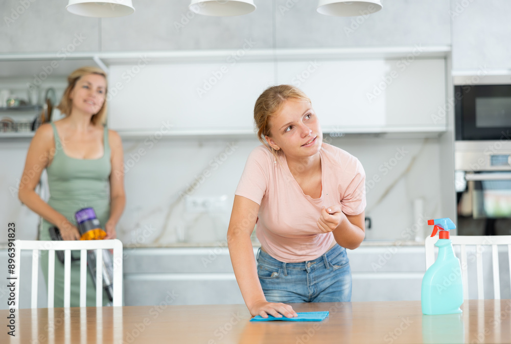 Positive mom and daughter are doing household chores together and ...