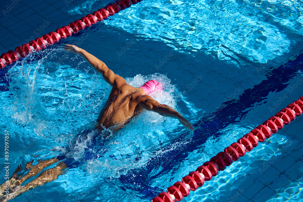 Swimmer in pink cap executes powerful butterfly stroke, his muscular ...
