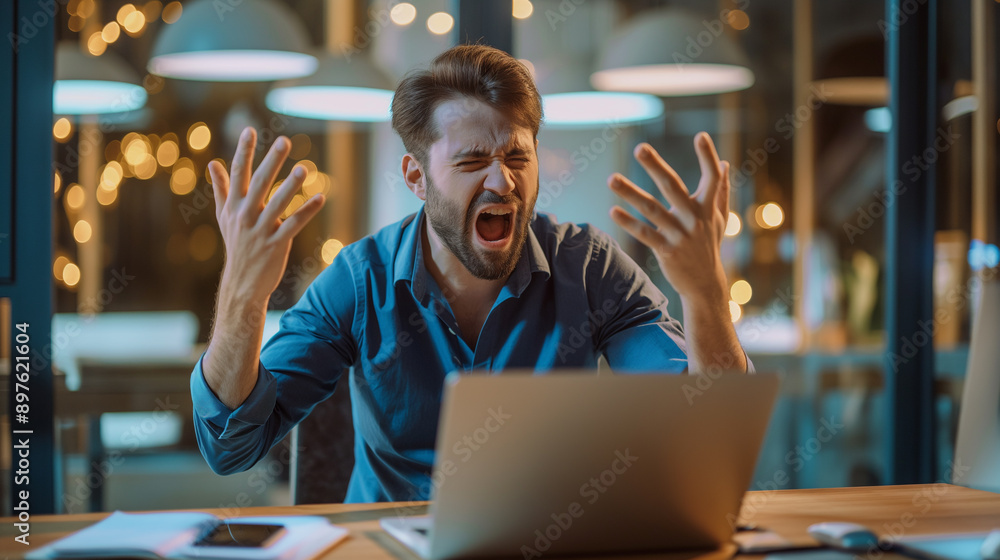 An agitated man in a blue shirt, sitting at a modern office desk ...