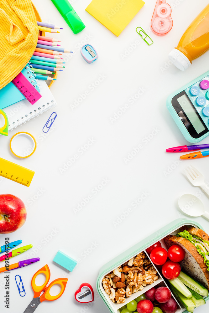 Frame of school supplies and a healthy lunchbox with fresh fruits ...