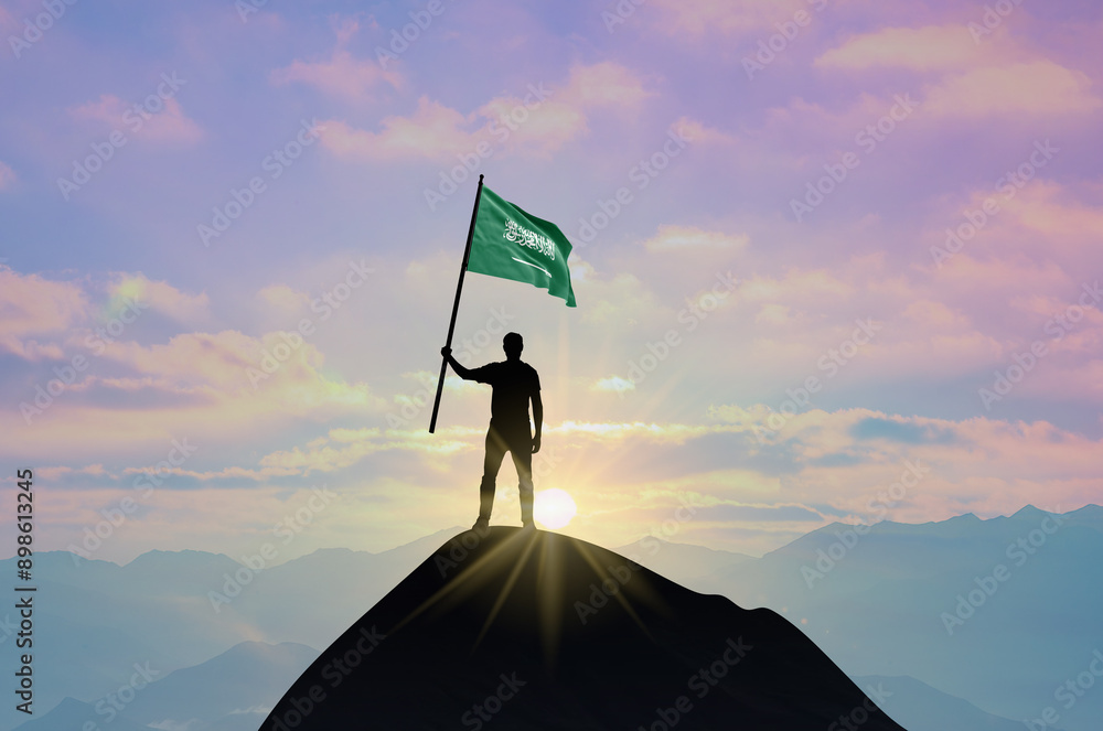 Waving flag of Saudi Arabia at the top of a mountain summit against ...
