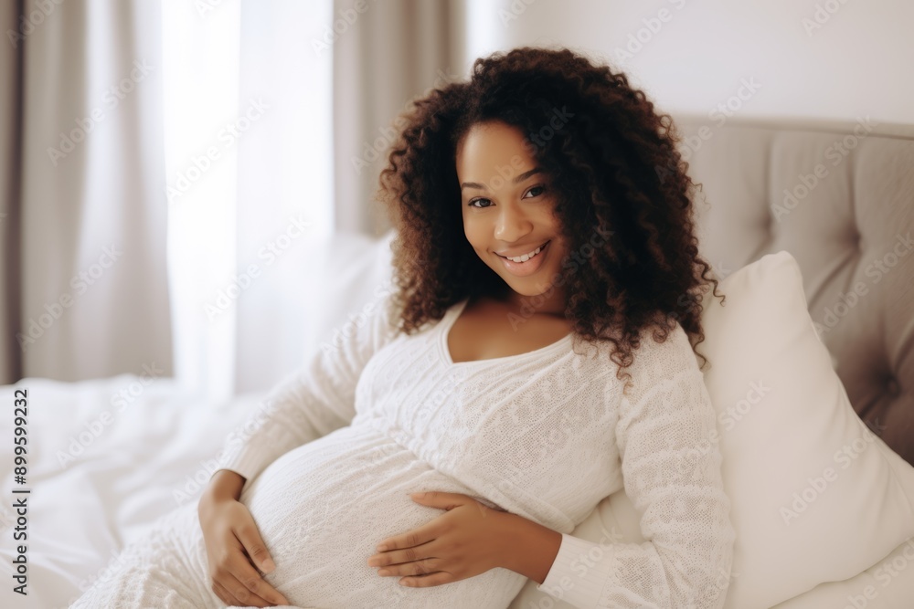 Joyful multiracial pregnant woman looking at her stomach expecting for ...