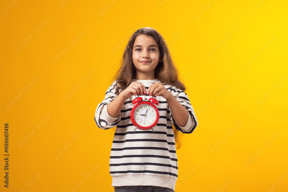 Smiling kid girl holding an alarm clock in hand. The concept of ...