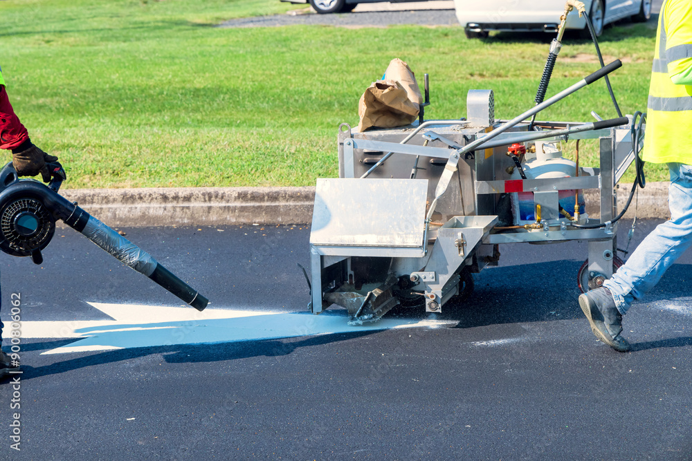 In order to mark road following laying of asphalt, workers use airbrush ...
