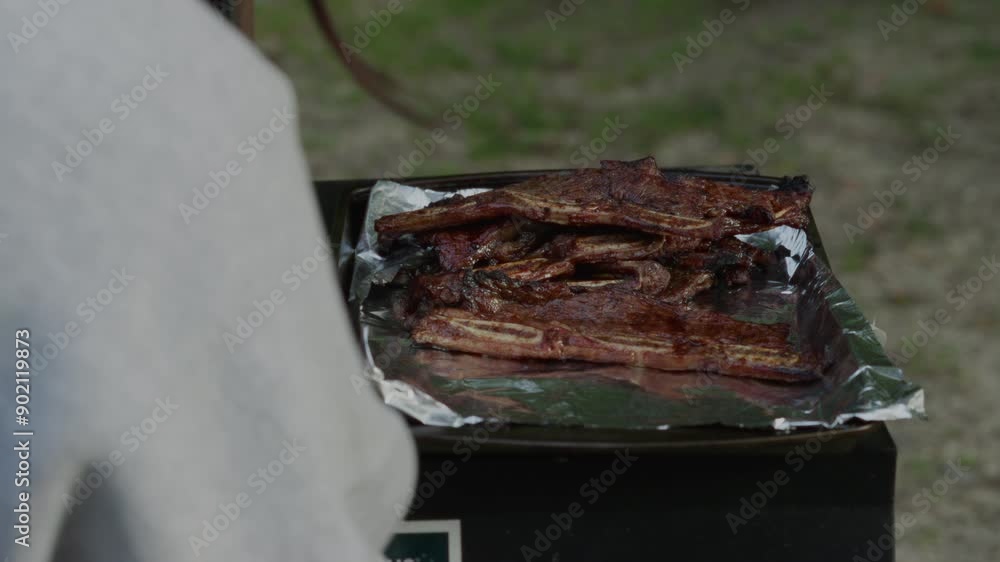 During the sunset, a woman grilled barbecue on a gas grill in the front ...