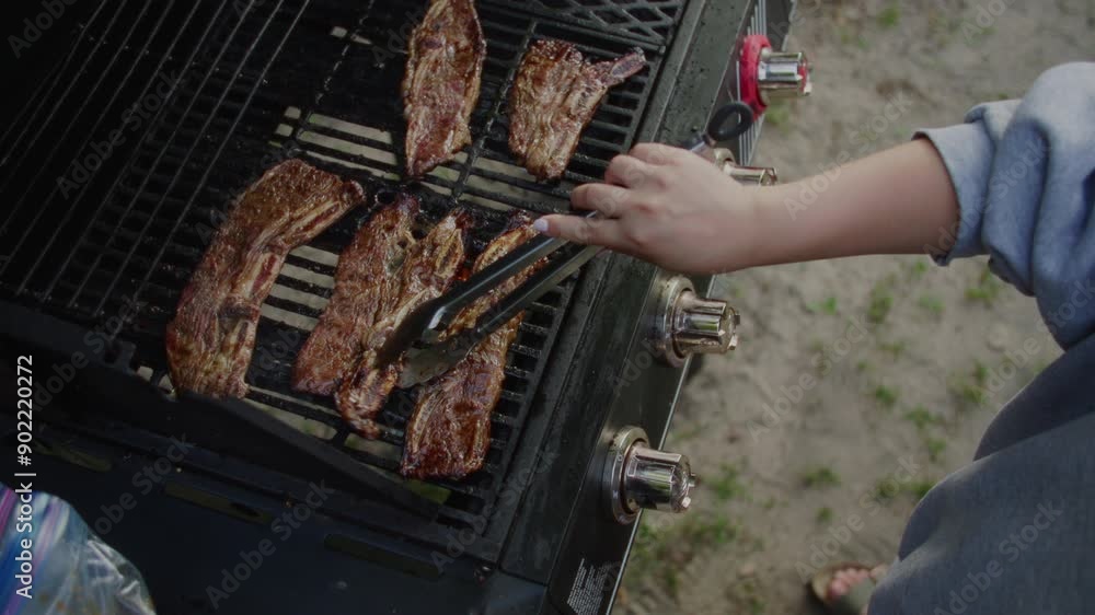 During the sunset, a woman grilled barbecue on a gas grill in the front ...