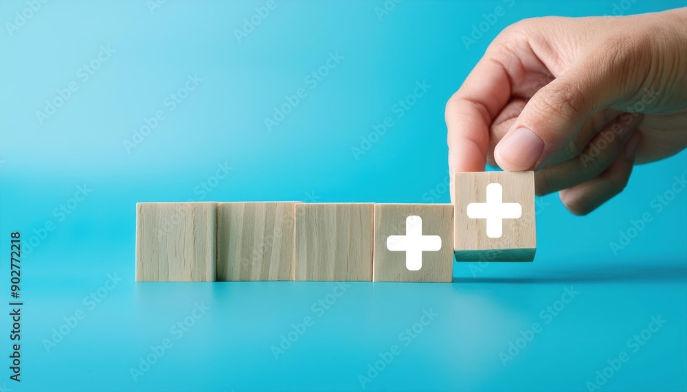 Value add concept. Hand place wooden cube with plus sign on light blue ...