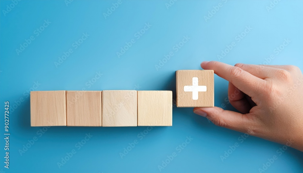 Value add concept. Hand place wooden cube with plus sign on light blue ...
