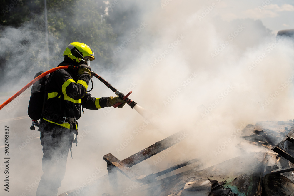 Firefighter equipped with breathing apparatus extinguishing waste fire ...