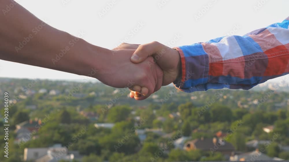 Two friends shaking hands on blurred cityscape background. Close up of ...